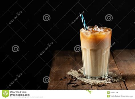 Ice Coffee In A Tall Glass With Cream Poured Over And Coffee Beans On A
