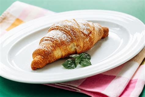 가루 설탕과 민트 잎이 현대적인 녹색 배경에 흰색 접시에 신선한 크루아상 수평 닫기 보기 건강한 식생활에 대한 스톡 사진 및