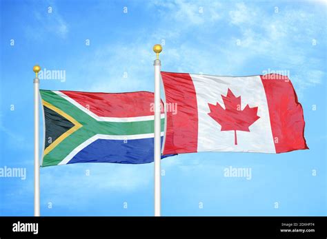 South Africa And Canada Two Flags On Flagpoles And Blue Sky Stock Photo