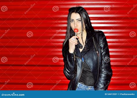 Brunette Girl Holding And Licking Round Red Sugar Candy Standing Stock