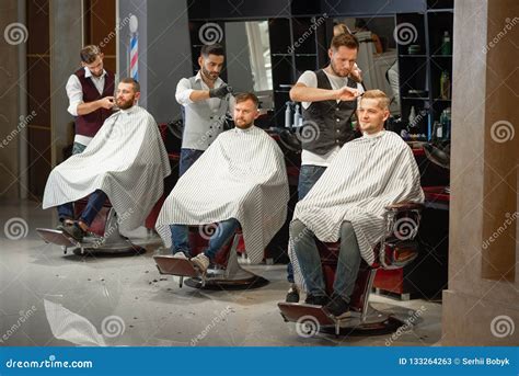 Tres Peluqueros Que Hacen Diseñar Del Pelo Y De La Barba En Peluquería De Caballeros Imagen De