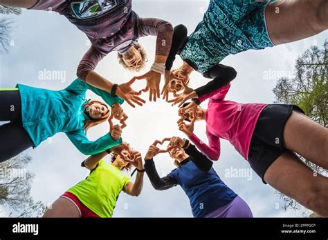 Group Of Female Athletes Runners In Circle Forming Hearts With Hands