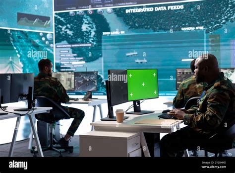 Soldier Gathering Real Time Surveillance Data Next To Mockup Display In High Tech Command Center