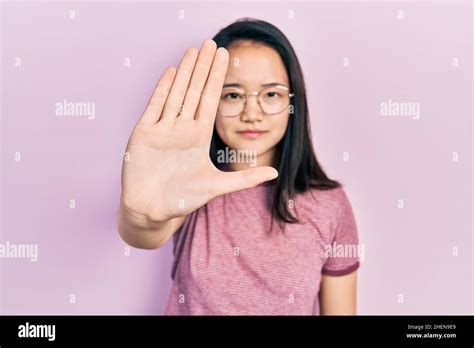 Young Chinese Girl Wearing Casual Clothes And Glasses Doing Stop Sing With Palm Of The Hand