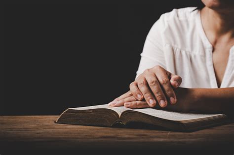 기독교 여성의 손을 거룩한 성경에 손을 대고 검은 배경을 가진 교회에서 하나님 께 감사하는 예배를하고 성인 여성 사람은 책 신앙