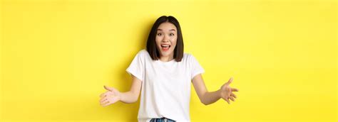 Возбужденная молодая азиатка раскинула руки как будто держит большой большой предмет