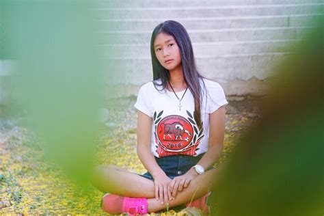 Premium Photo Portrait Of Girl Sitting On Field In Park