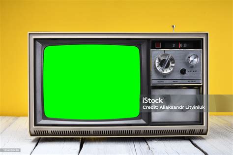 비디오와 이미지를 추가하기위한 녹색 화면이있는 오래된 빈티지 1970 년대 Tv는 노란색 배경에 나무 테이블에 서 있습니다