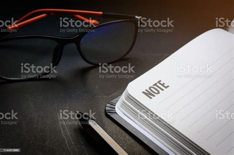 극적인 조명 톤의 검은 색 책상 배경에 검은 펜과 안경 오픈 빈 라인 노트북을 닫습니다 비즈니스 계획 또는 일기에 대 한