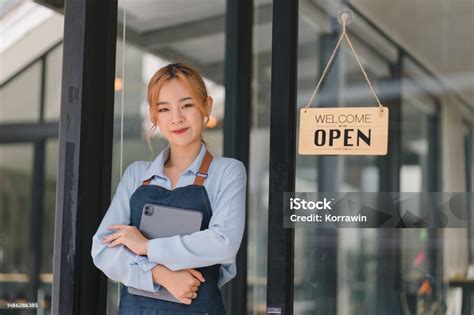 카운터에 서 있는 자신감 넘치는 여성 바리스타의 초상화 앞치마를 두른 여성 카페 주인이 카메라를 바라보며 웃으며 손님을 맞이한다 여성에 대한 스톡 사진 및 기타 이미지