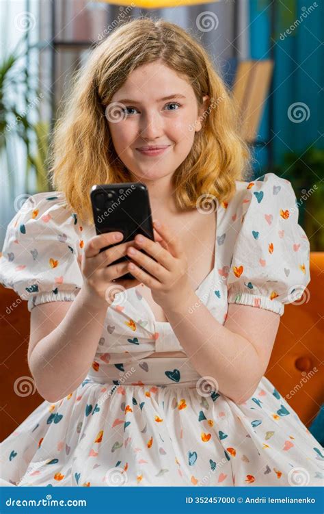 Young Woman Sitting On Sofa At Home Using Smartphone Share Messages On