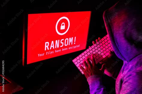 Computer Screen With Ransomware Attack Alert In Red And A Hacker Man Keying On Keyboard In A