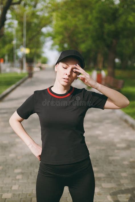 Young Tired Athletic Beautiful Brunette Girl In Black Uniform And Cap