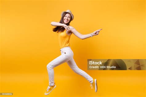 흥분된 웃는 영 행복의 노란색 오렌지 배경에 고립 된 공간을 복사 밀 짚 여름 모자 높은 여자를 점프 합니다 사람들이 진심으 감정 열정 라이프 스타일 개념 광고 영역입니다