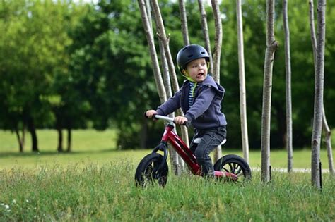 공원 잔디밭에서 밸런스 자전거를 타고 있는 어린 유아 소년 헬멧과 스포티한 의상을 입은 어린이는 화창한 날에 야외 활동과 신체 활동을 즐깁니다 2 3 살에 대한 스톡 사진