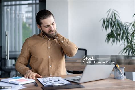 나무 책상 위에 문서와 안경을 놓고 현대적인 사무실 환경에서 노트북으로 작업하는 동안 목에 불편함을 겪고 있는 사업가 인체공학에 대한 스톡 사진 및 기타 이미지 Istock
