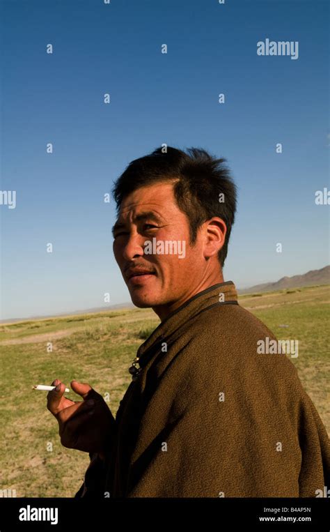 A Mongolian Nomad Enjoys A Smoke In The Vast Mongolian Grasslands Stock