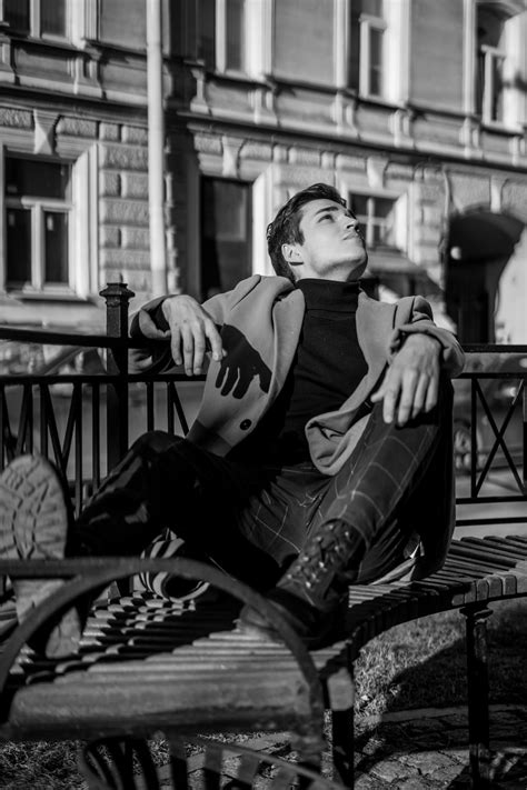 Man In Black And White Crew Neck T Shirt And Black Pants Sitting On