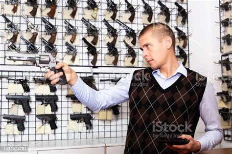 Photo Libre De Droit De Lhomme Choisit Le Revolver Dans Le Magasin
