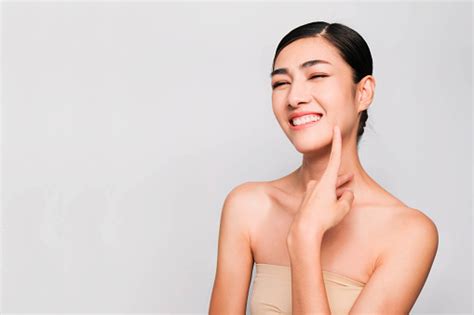 깨끗하고 밝은 피부와 젊은 아름다운 아시아 여자 화장품 뷰티 개념 손이 뺨에 터치 회색 배경에 고립 미소와 친절한 얼굴 건강