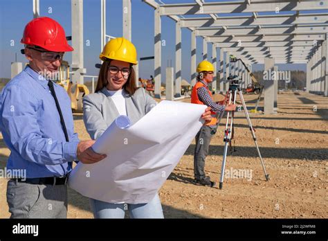 Man And Woman In Hardhats Disscus A Construction Project On Site Gender Equality At Work Stock