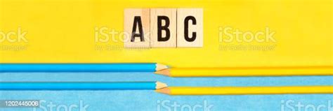 노란색과 밝은 파란색 유니버설 두 톤 종이 배경에 나무 블록과 여러 가지 빛연필의 Abc 문자의 파노라마보기 학교 시작 사무실과