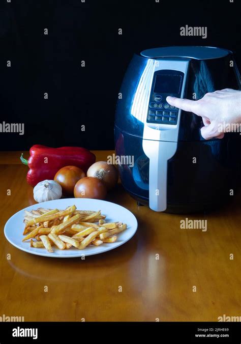 A Woman S Hand Programming An Air Fryer With French Fries And