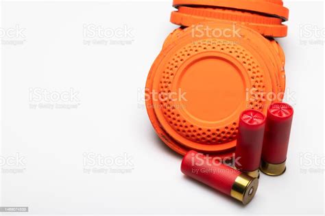 Stack Of Clay Shooting Target With Red Shotgun Shell Bullets On White
