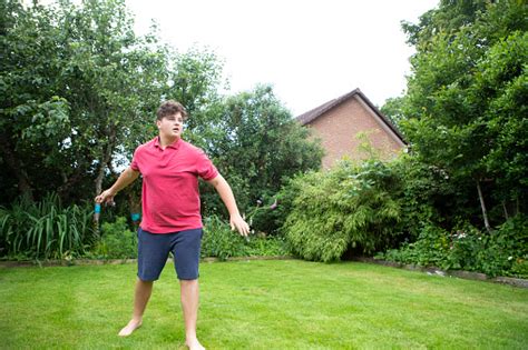 뒷뜰의 잔디밭에서 캐치를 연주하는 십대 소년 그는 빨간 폴로 셔츠와 파란색 반바지를 입고 있다 16 17 살에 대한 스톡 사진 및 기타 이미지 Istock