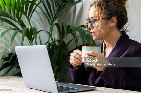전문 기업가의 초상화는 모니터 컴퓨터에서 비즈니스 뉴스를 읽고 컵에서 술을 마신다 혼자 실내 사무실 직장의 책상에서 노트북으로