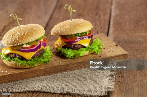 식사 음식 커틀릿 구이 양상추 토마토 치즈 오이가 있는 두 개의 햄버거가 밝은 나무 배경에 있습니다 0명에 대한 스톡 사진 및 기타 이미지 Istock