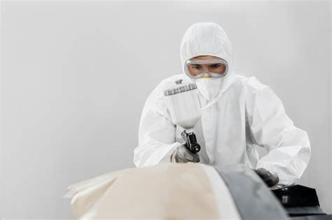 Pintor De Sexo Masculino Que Usa El Arma Para Pintar El Coche En La Tienda Foto Gratis