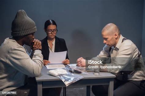 안경을 쓴 아름다운 여성 변호사가 흑인 마약 중독자의 심문 중에 증거에 익숙해집니다 가정의 방에 대한 스톡 사진 및 기타 이미지