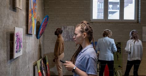 현대 미술관의 다른 손님에 대해 벽에 그림을 보고 있는 향취를 가진 젊은 여성의 측면 모습 사진 Unsplash의 창조성 이미지