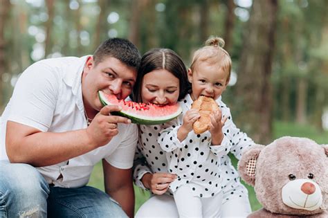 피크닉에서 수박을 먹는 행복한 가족의 휴일 야외 초상화 엄마 아빠와 딸과 함께 공원에서 즐거운 시간을 보내고 있습니다 선택적 초점 가족에 대한 스톡 사진 및 기타 이미지