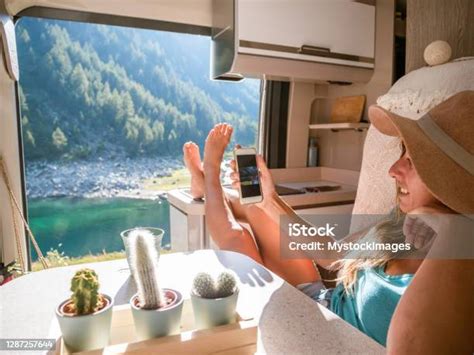 행복한 여자는 알파인 호수가 내려다 보이는 밴 안에 그녀의 휴대 전화를 사용 여행 주제에 대한 스톡 사진 및 기타 이미지 여행 주제 캠핑카 휴대전화 Istock