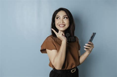 A Portrait Of A Happy Asian Woman Is Smiling And Holding Smartphone