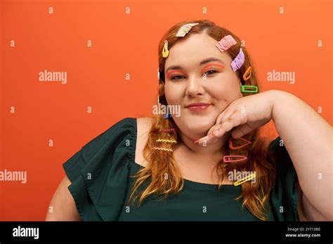 A Joyful Plus Size Woman Poses Playfully In Front Of A Bold Orange