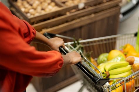 Mulher empurrando carrinho de compras no supermercado Foto Grátis