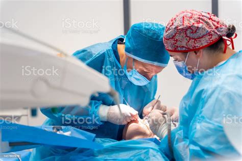 치과 진료소 파란색 정장과 모자를 쓴 여성 치과 의사가 구강 수술을 수행합니다 수술에 대한 스톡 사진 및 기타 이미지 수술