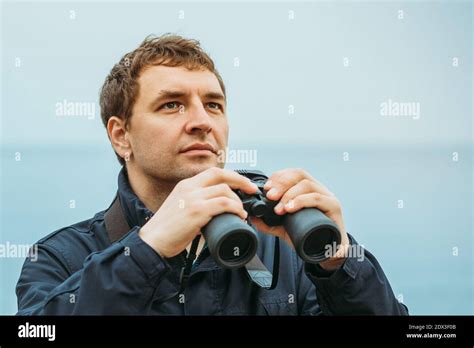 A European Man On A Sea Background Is Holding Binoculars In His Hands
