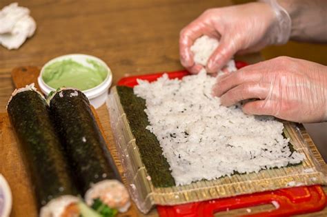 초밥과 롤을 만드는 과정 집에서 또는 부엌 테이블에 레스토랑에서 전통적인 일본 음식을 준비 하는 남자 요리사 손의 클로즈업 고급