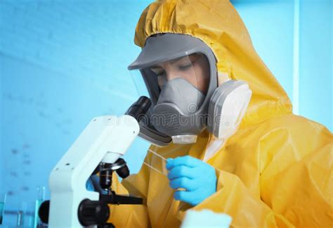 Scientist In Chemical Protective Suit Using Microscope Virus Research