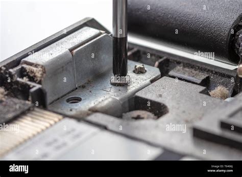 The Screwdriver Unscrews The Fastening Bolt Of The Old Dusty Processor Computer Board