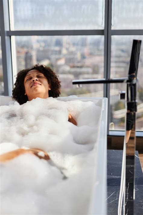 Relaxed Black Woman Taking Foamy Bath Lying In Bathtub Indoors Stock