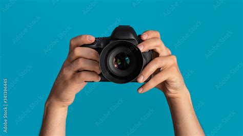 Closeup Of Photographer Pointing Dslr Camera At Screen Blue Background