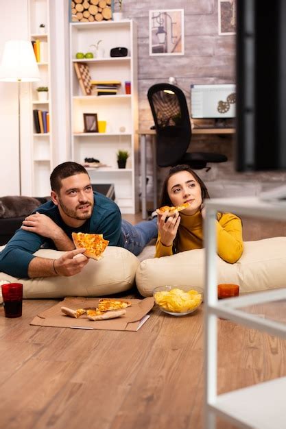 Pareja sentada en el suelo y viendo la televisión en su sala de estar