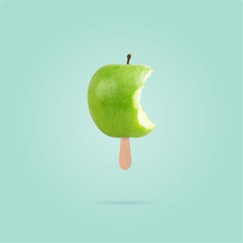 파스텔 파란색 배경에 아이스크림 막대가 있는 녹색 물린 사과 다이어트 건강 개념입니다 프리미엄 사진