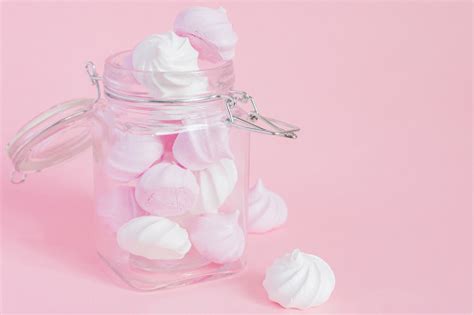 핑크 바탕에 유리 항아리에 흰색과 분홍색 트위스트 머 랭 설탕을 휘 핑 하 고 달걀 흰 자를 구워 만든 프렌치 디저트 복사