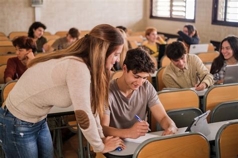Professor explicando ao aluno individualmente em uma sala de aula universitária Foto Premium